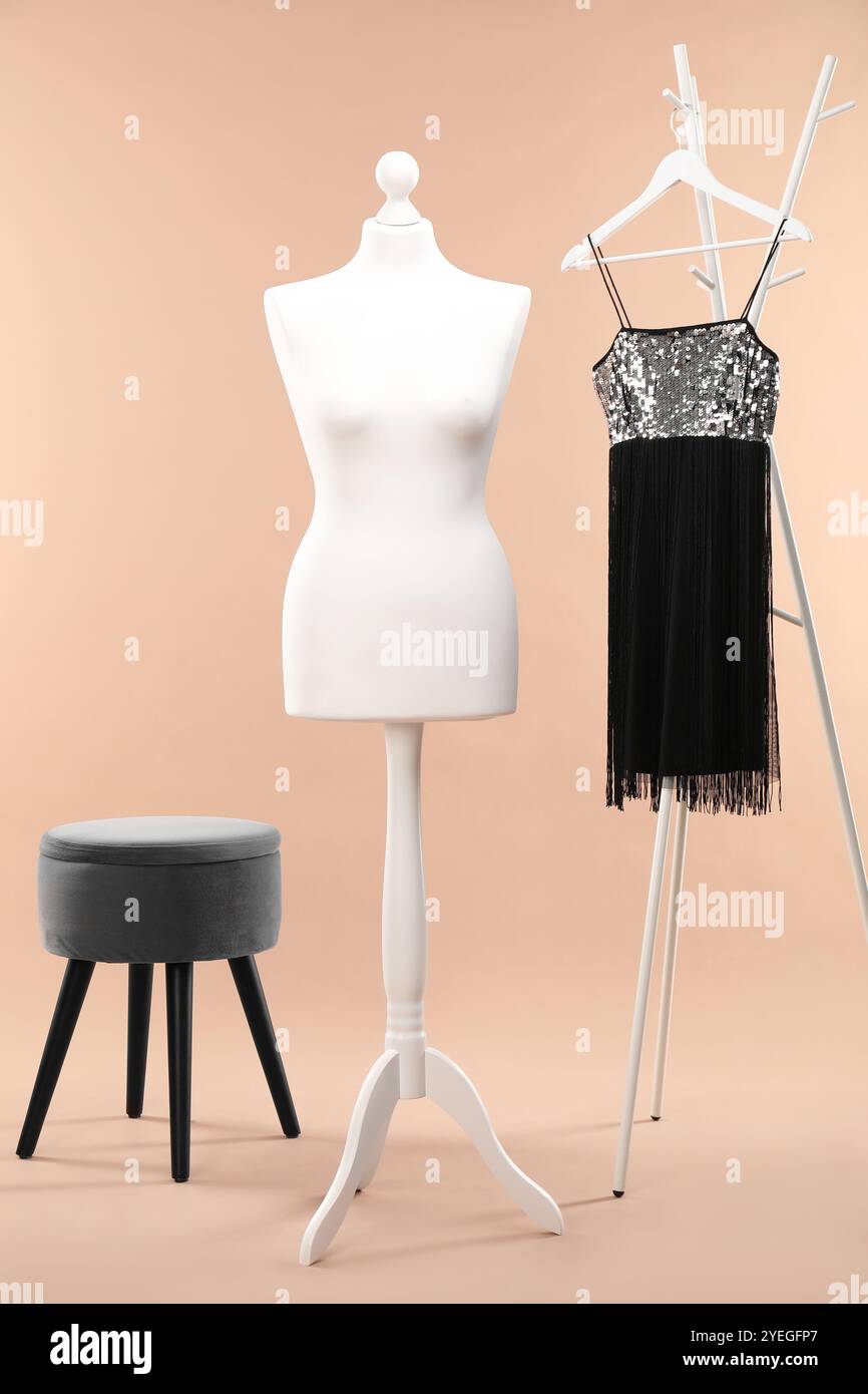 One female mannequin, rack, dress and ottoman on beige background Stock ...