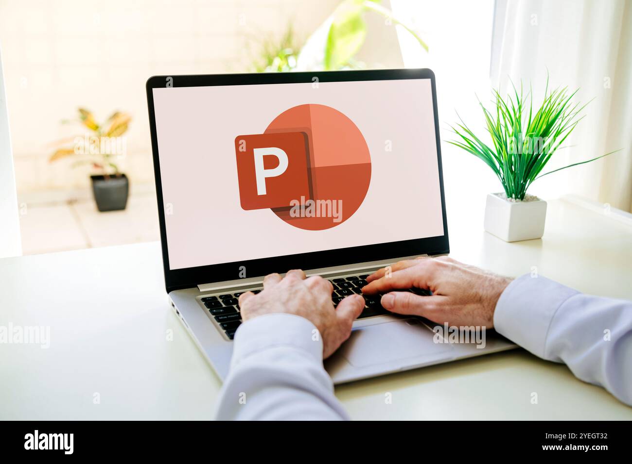 Man using a laptop computer displaying logo of Microsoft Office PowerPoint on the screen. Power ...