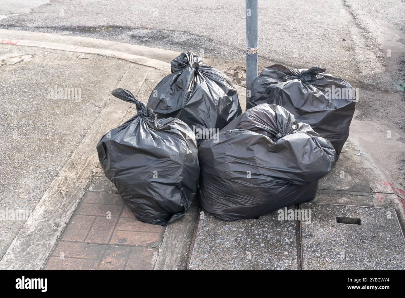 Front view of garbage in black plastic bag at garbage dump on roadside ...