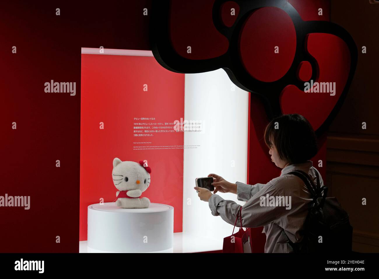 A visitor takes a picture of a Hello Kitty doll at the exhibition "As I ...
