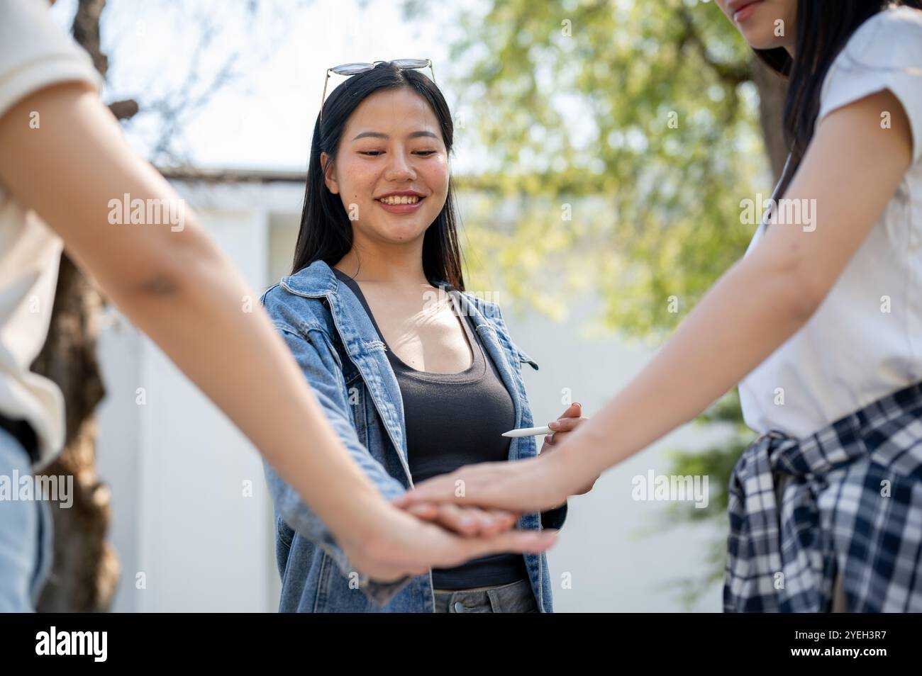 A close-up of college students putting their hands together while ...