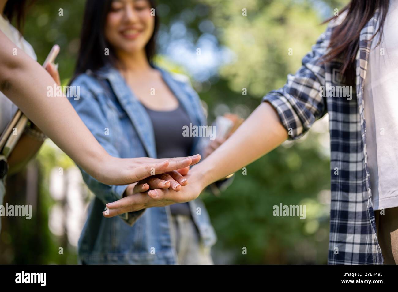 A close-up of college students putting their hands together while ...