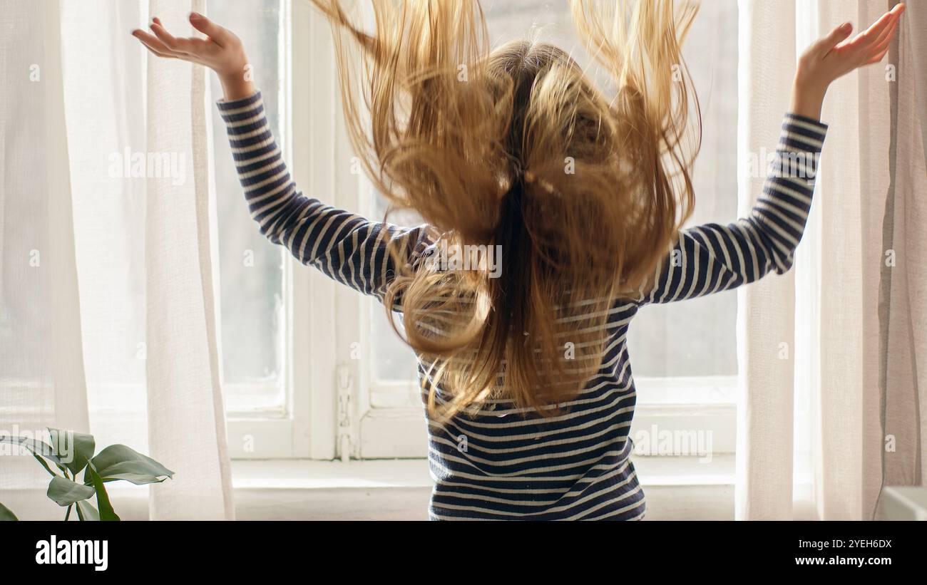 Little girl window shake healthy hair going looking at camera smiling ...