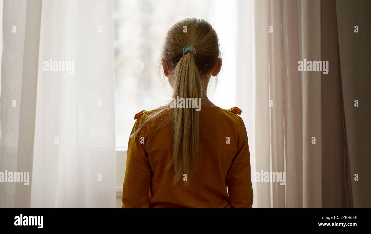Back view little girl looking out window turn around leave child kid ...