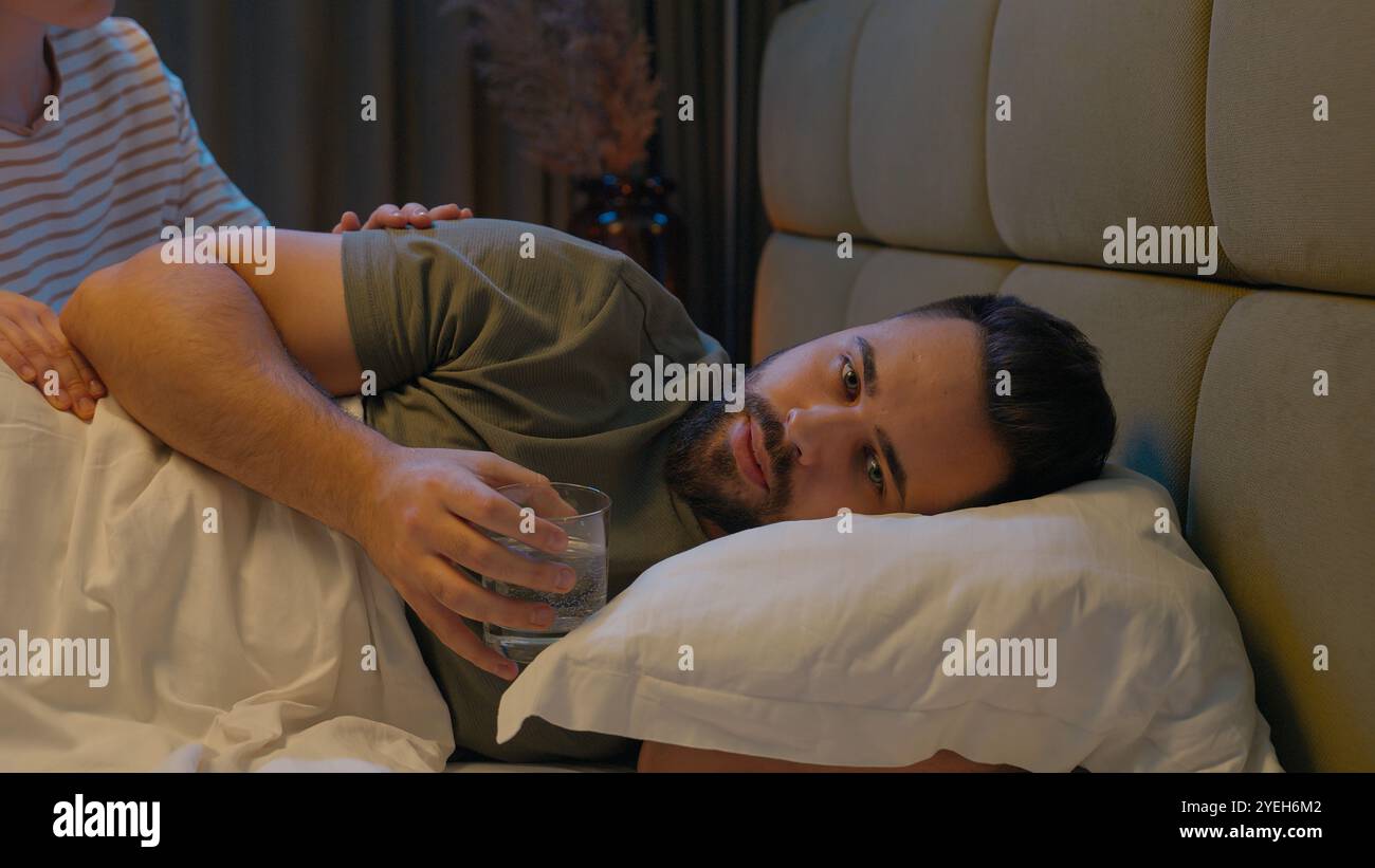 Sick man lying on bed illness runny nose woman holding glass water care ...