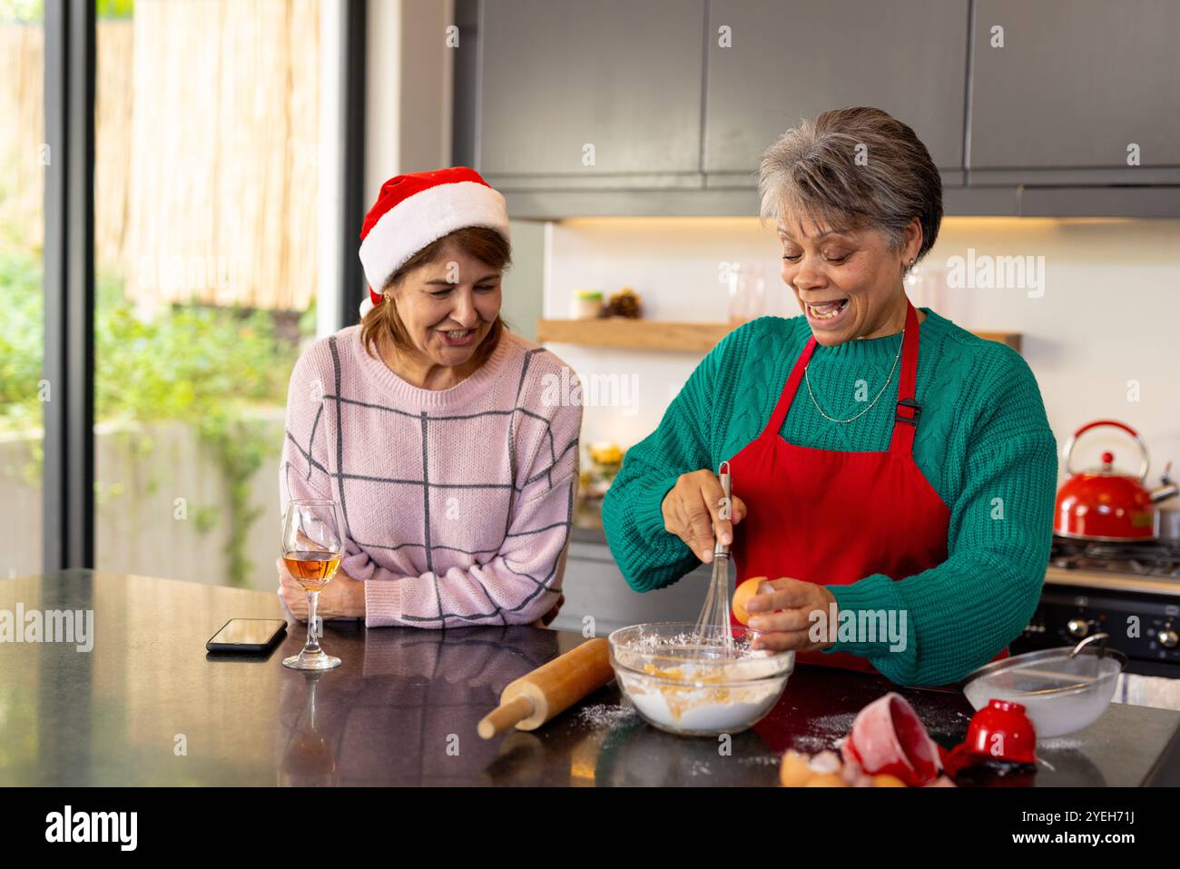 Christmas time, senior female friends baking together in kitchen, at ...