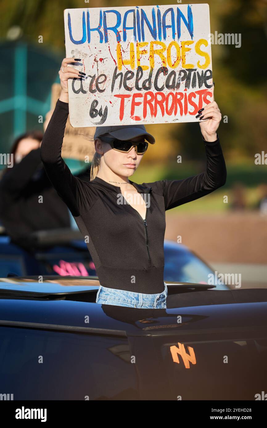 Young Ukrainian girl demonstrating a poster "Ukrainian Heroes Are Held ...