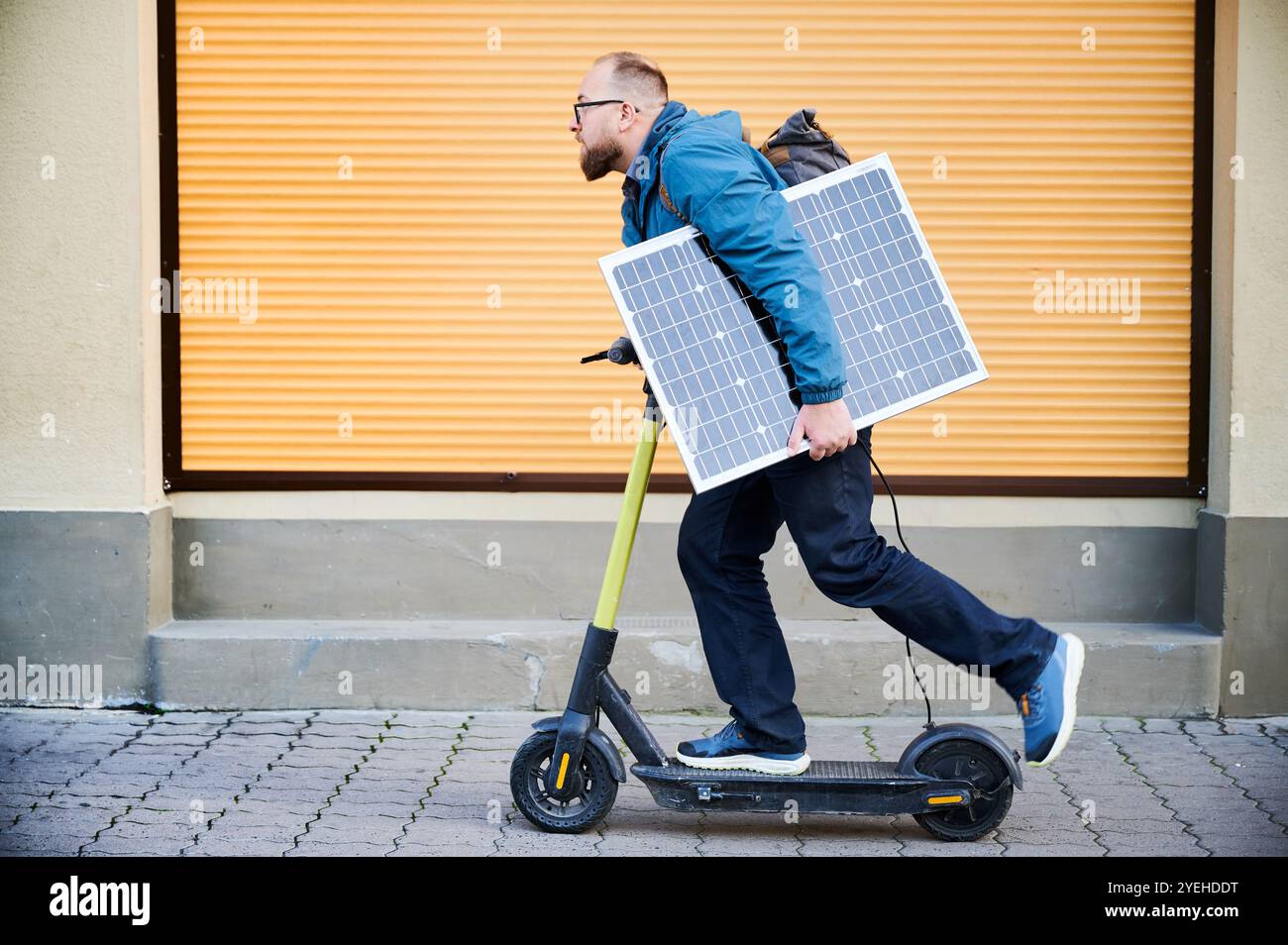Man rides electric scooter while carrying solar panel. Integration of ...