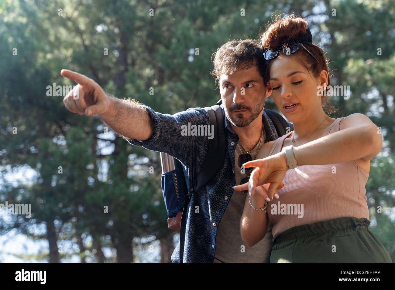 Adult couple navigating with smartwatch during hike in pine forest. Man ...