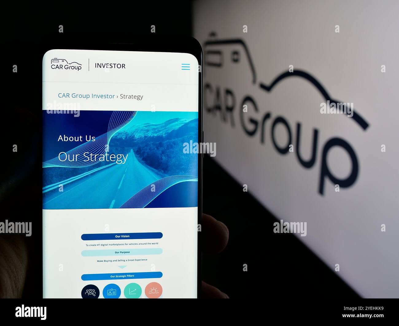 Person holding cellphone with webpage of Australian company CAR Group ...