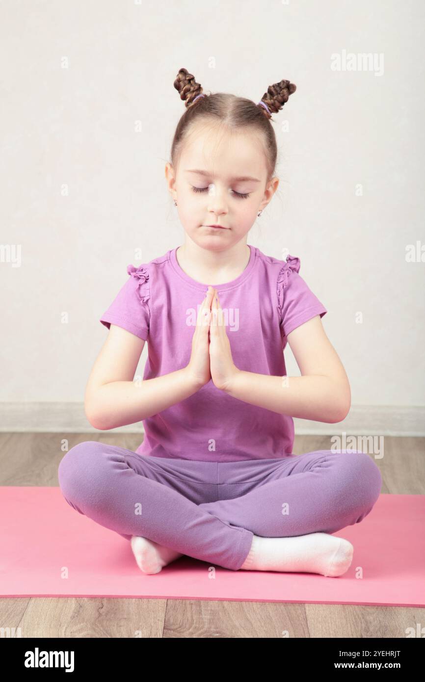 Charming little girl is smiling while doing yoga. top view Stock Photo ...