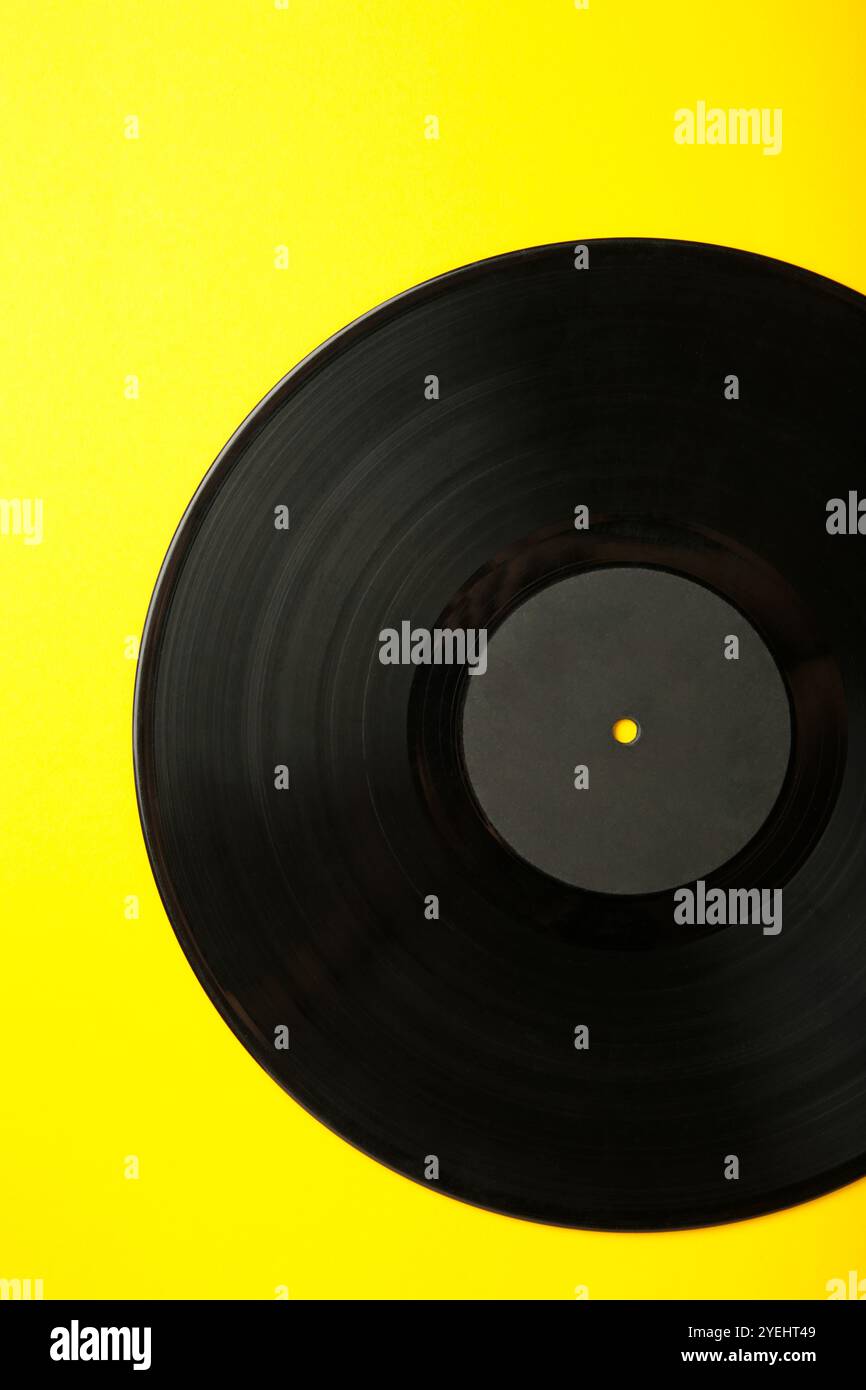 Gramophone vinyl record on yellow background. Vertical photo. Top view ...