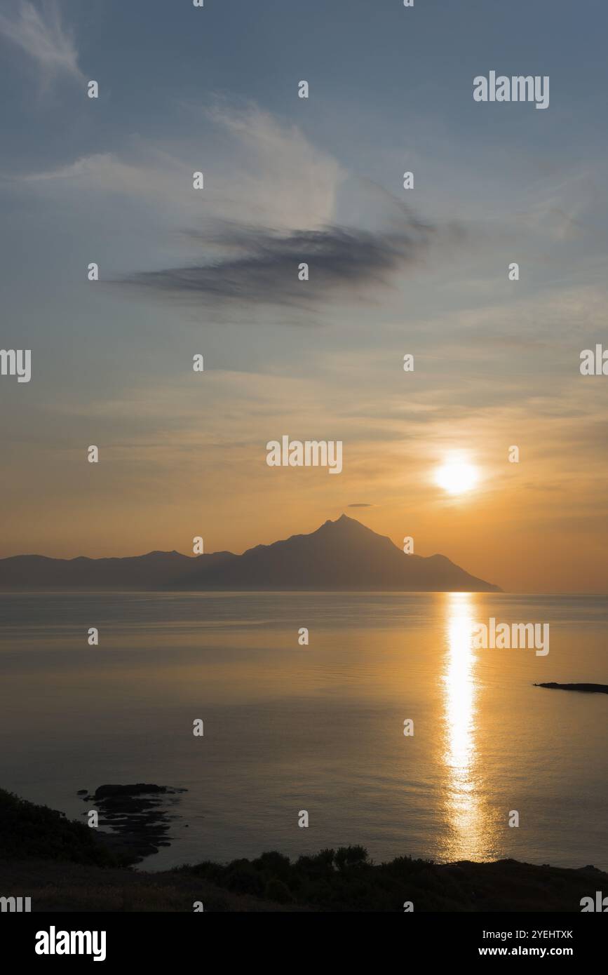 Sunrise over a mountain with clouds and reflections on the water ...