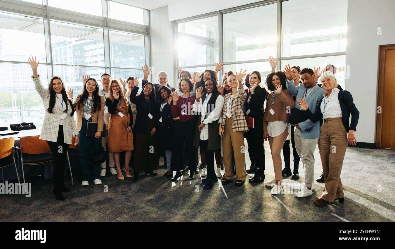A diverse group of people waving enthusiastically at a seminar ...