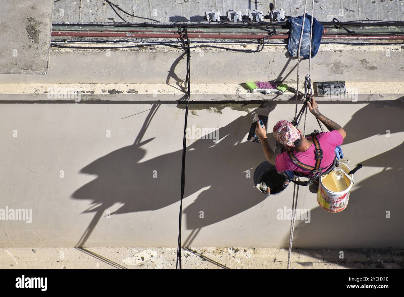 Painter hanging from a rope while working on a facade, symbolic image ...