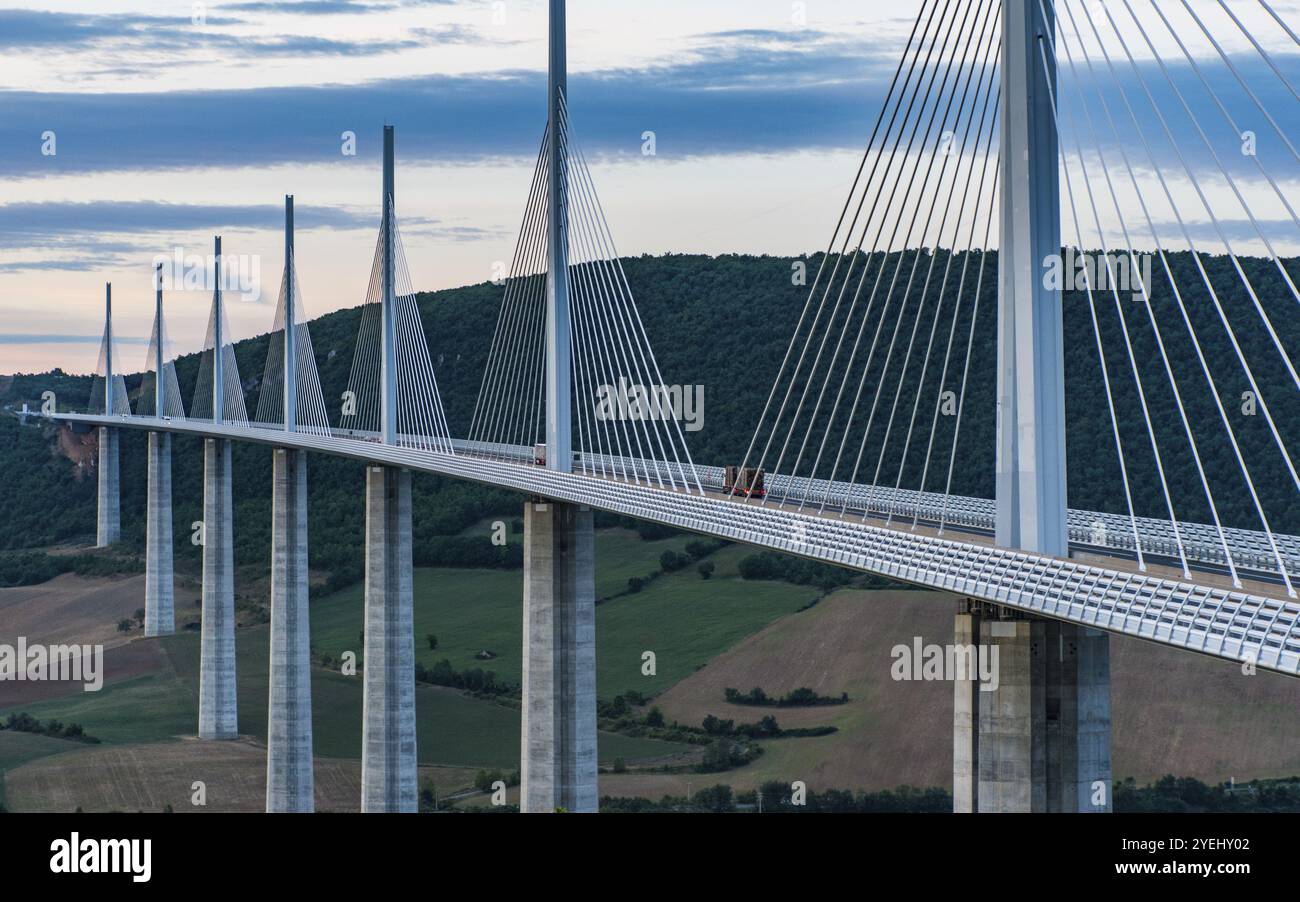 A modern cable-stayed bridge with steel wires spans over a lush ...