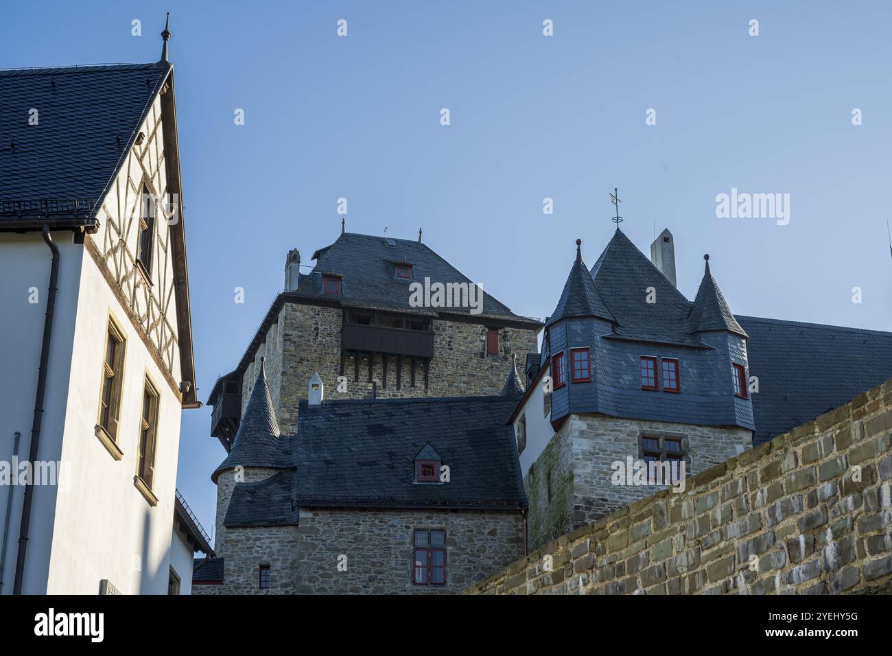 Old castle with stone walls and half-timbered facades under a clear ...