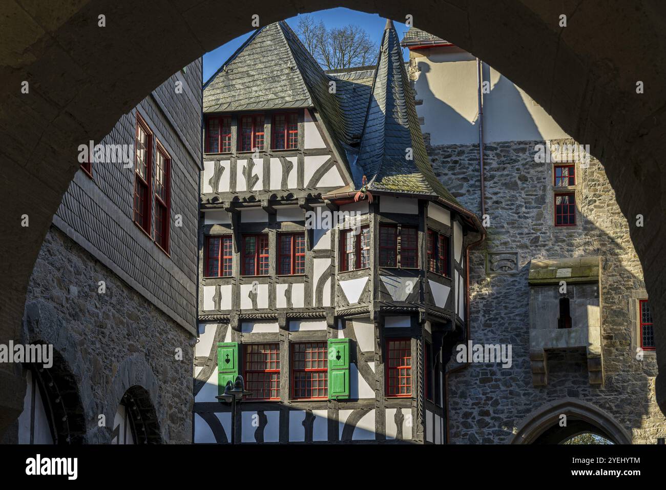 Medieval half-timbered house with green shutters behind a stone arcade ...