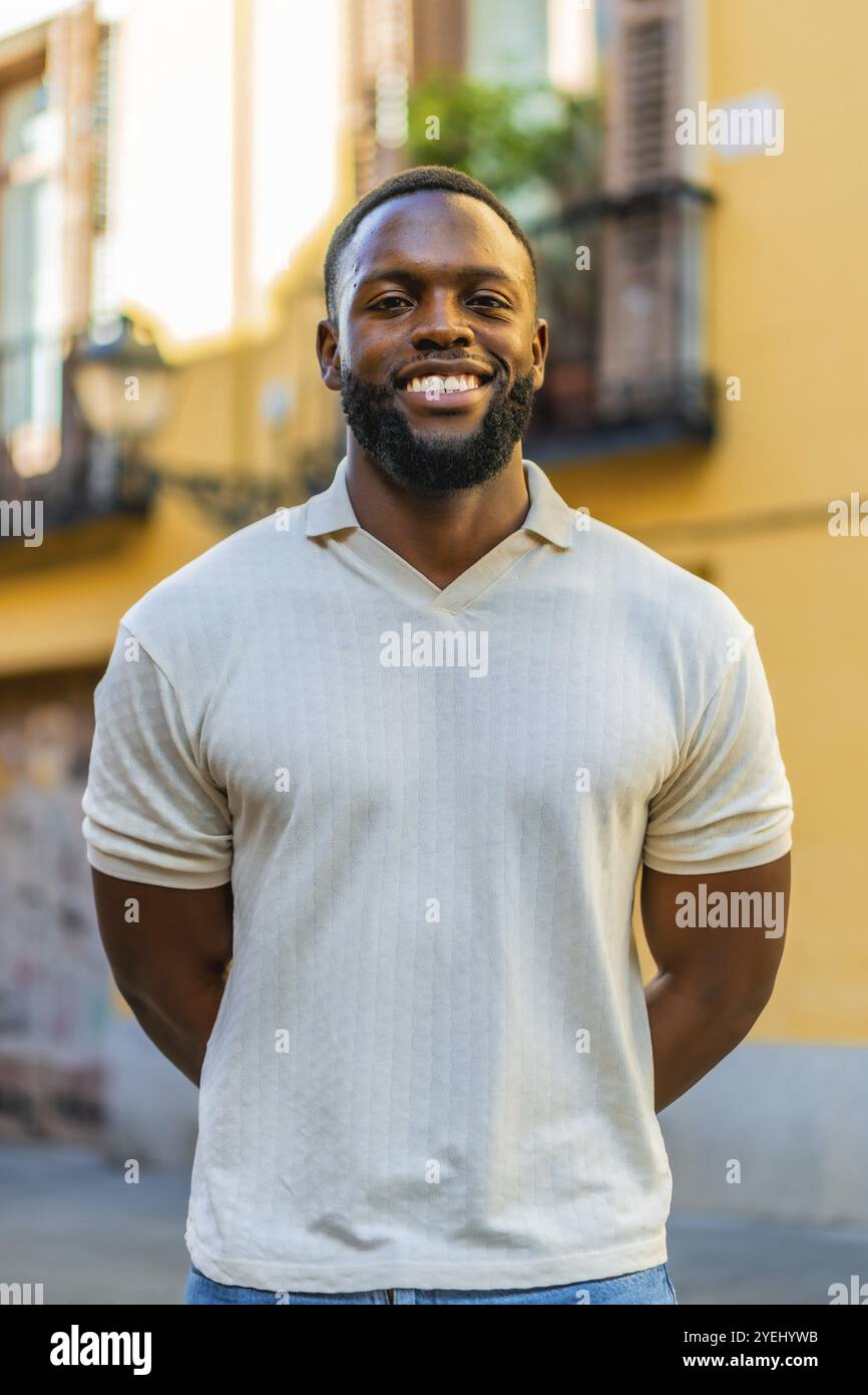 Vertical portrait of an african man with hands on back smiling at ...