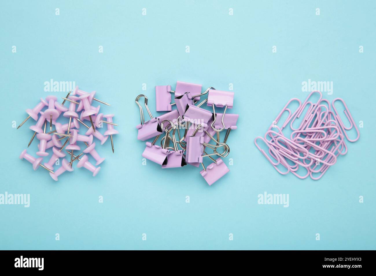 Set of purple paper clips, binders and pins on blue background. Top ...