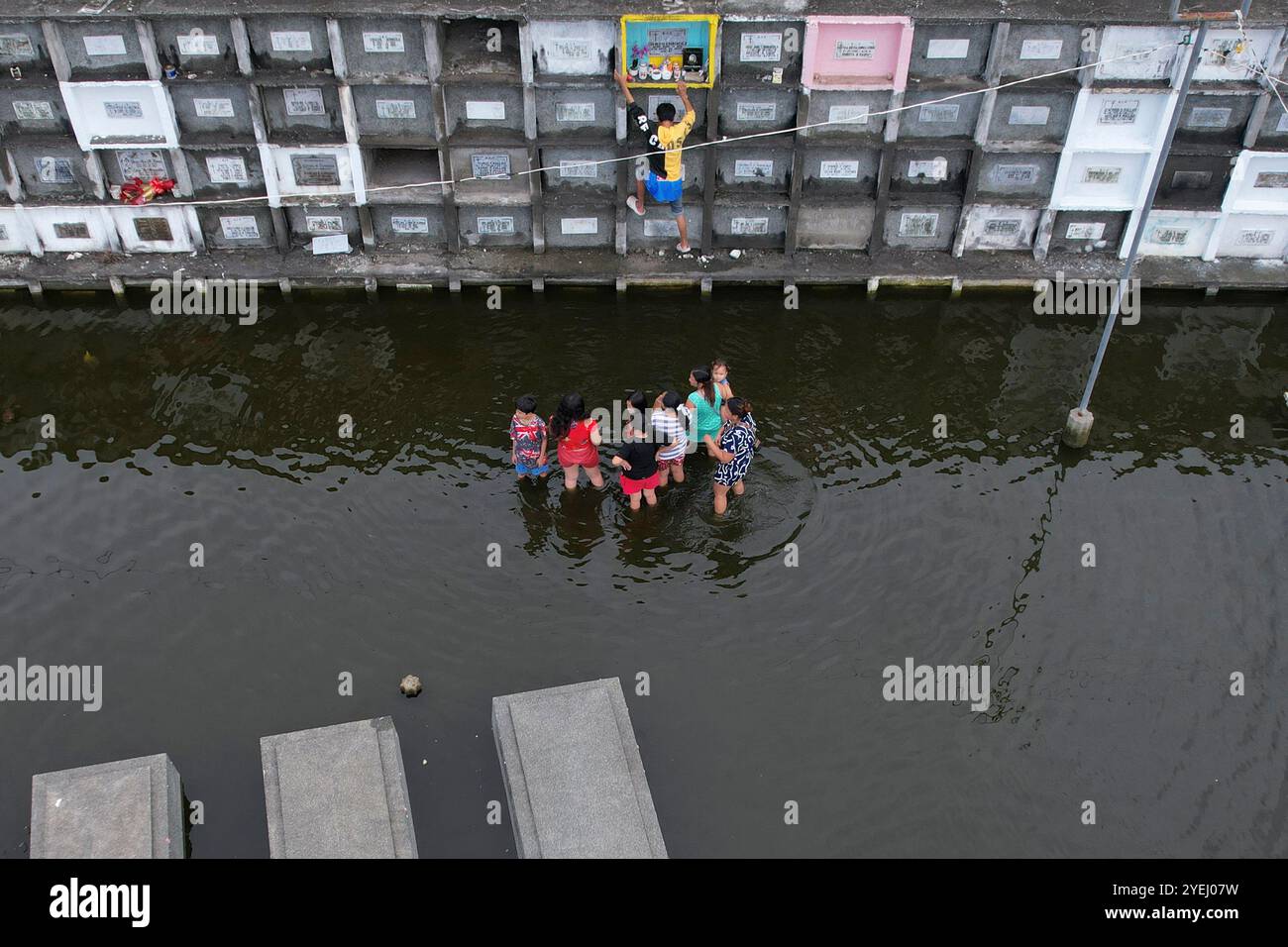People visit the tomb of family members at flood-prone Holy Spirit ...