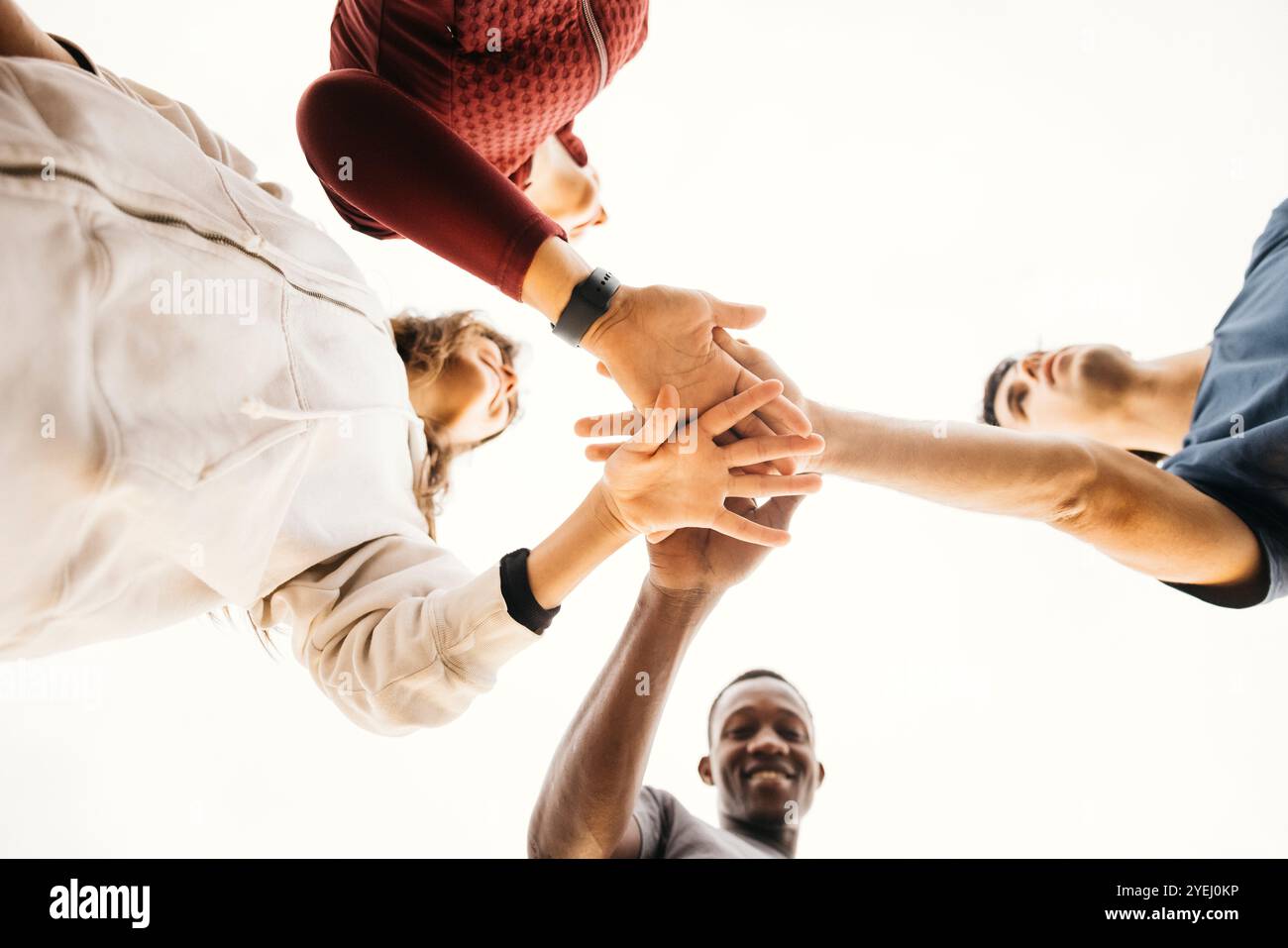 Low-angle shot of a diverse group of friends cheerfully joining their ...