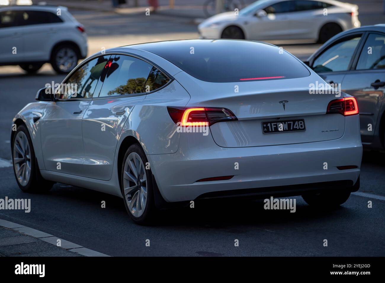 Tesla Model 3, showing its sleek design as it drives through a city ...