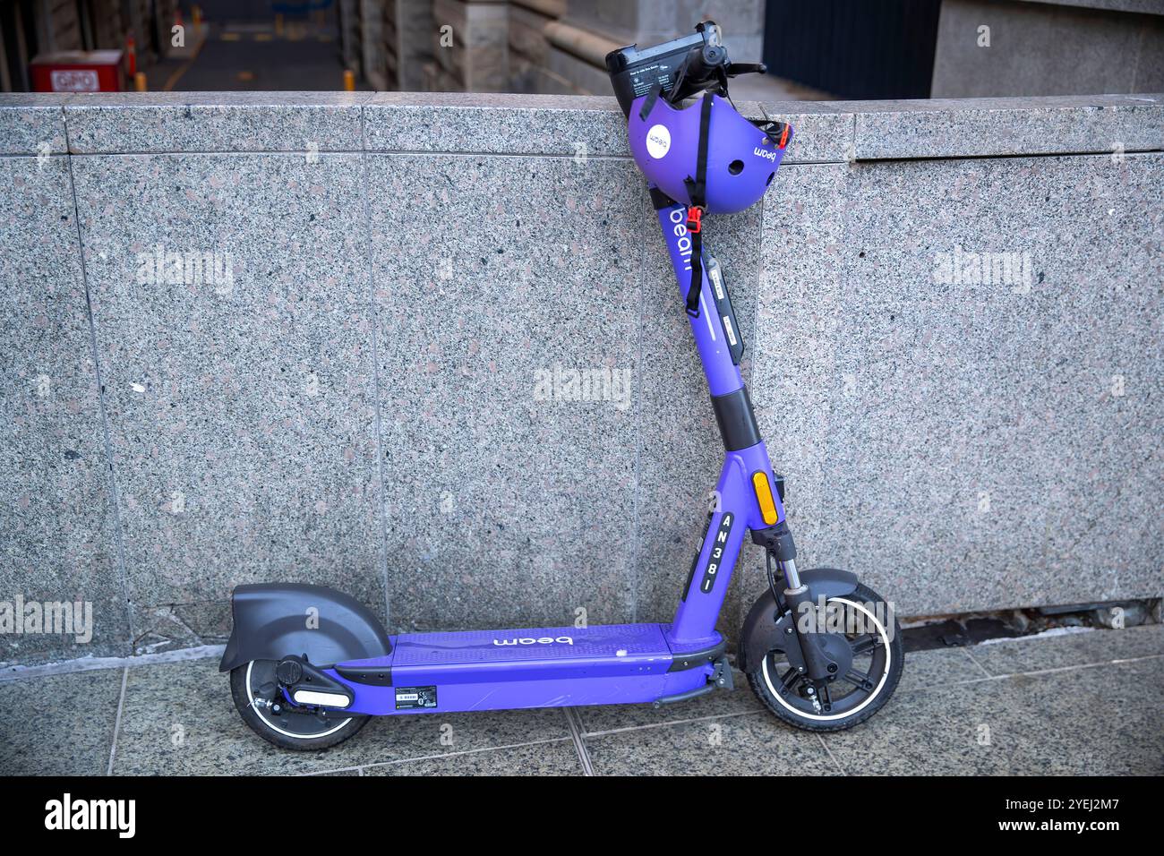 A purple Beam electric scooter, equipped with a matching helmet, leans ...