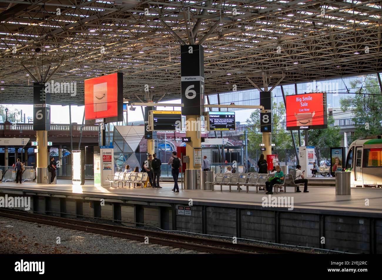 The image captures a busy train station with multiple platforms ...