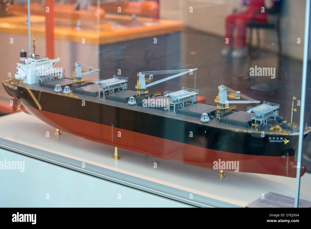 The photo features a detailed model of a cargo ship, displayed in a ...