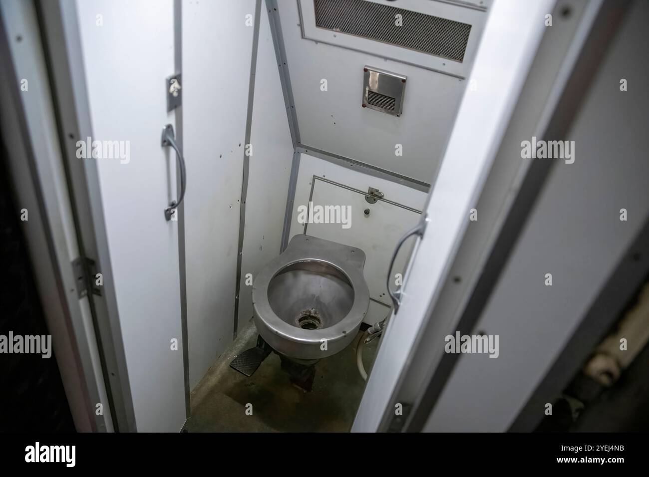 Interior view of a metal toilet in a confined restroom area, likely ...