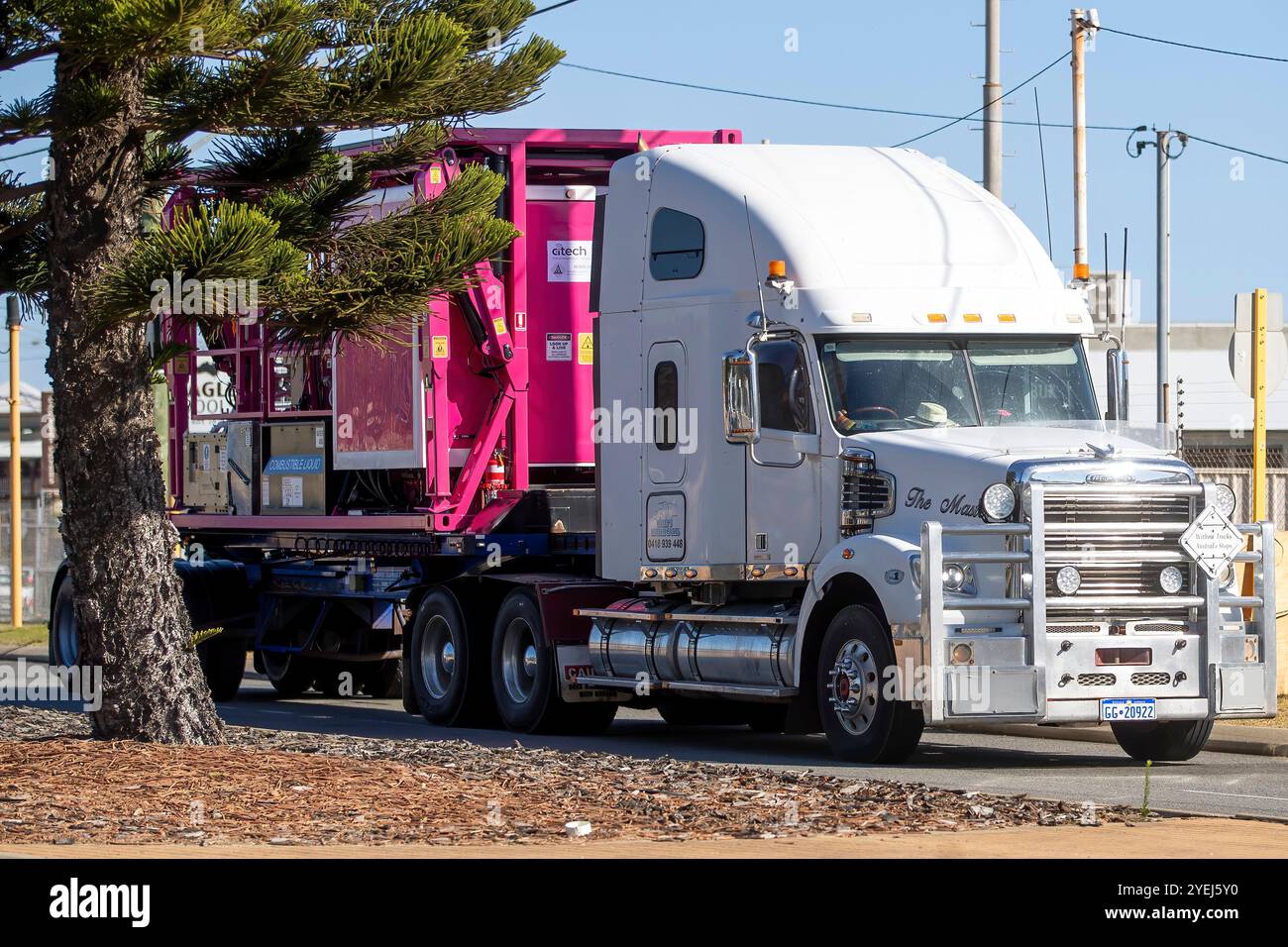 white semi-trailer truck hauling a vibrant pink container labeled ...