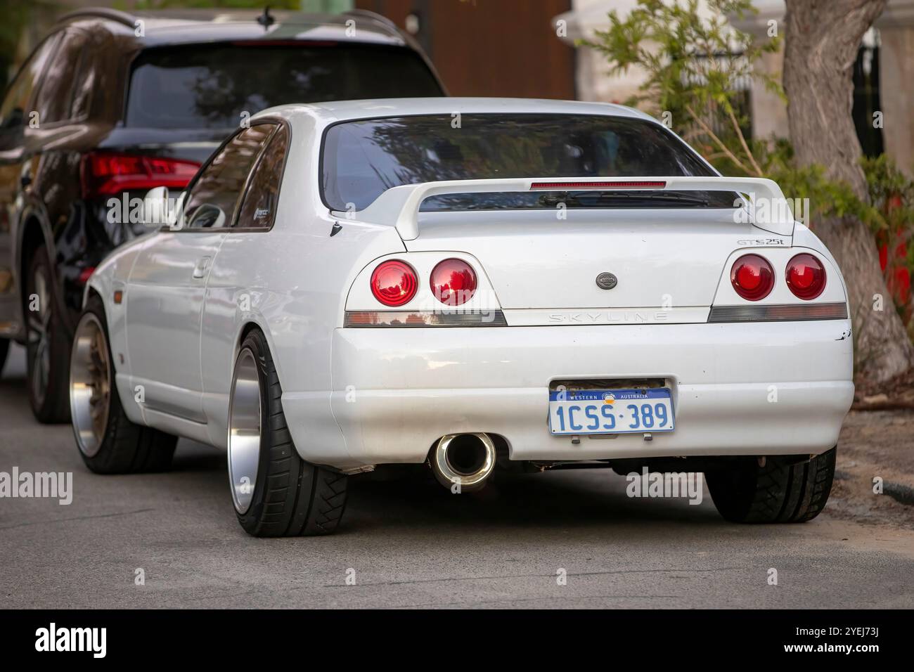 white Nissan Skyline parked on a suburban street, featuring aftermarket ...