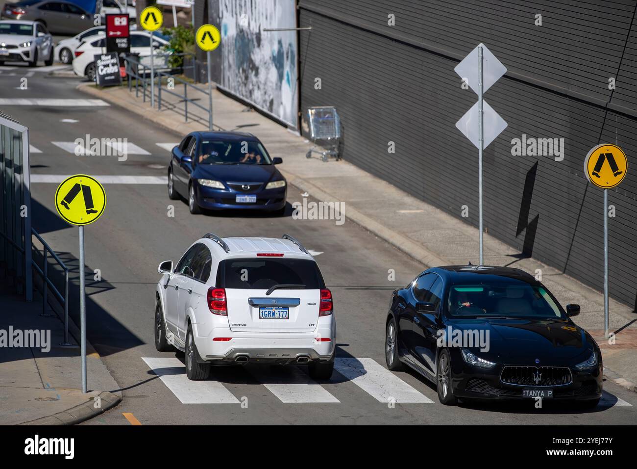 A parking lot scene featuring a white Holden Captiva, a black Maserati ...