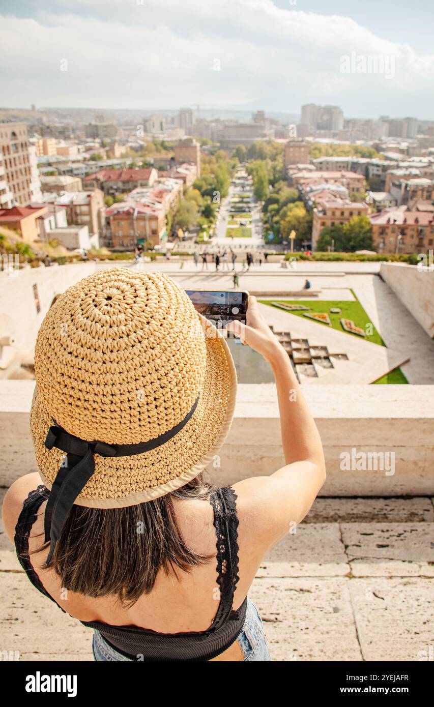 Back view woman taking pictures of a scenic urban landscape in Yerevan ...