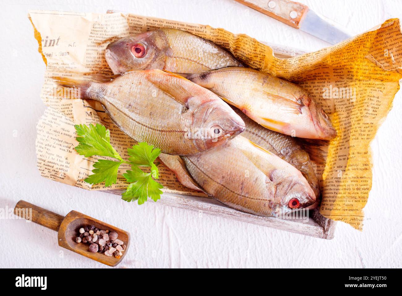 Raw fish on paper on a table. They appear to be fresh and ready to cook ...