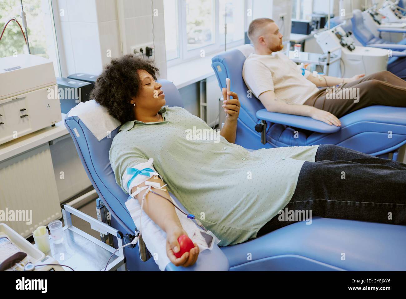 People reclined donating blood in medical facility, holding stress ...