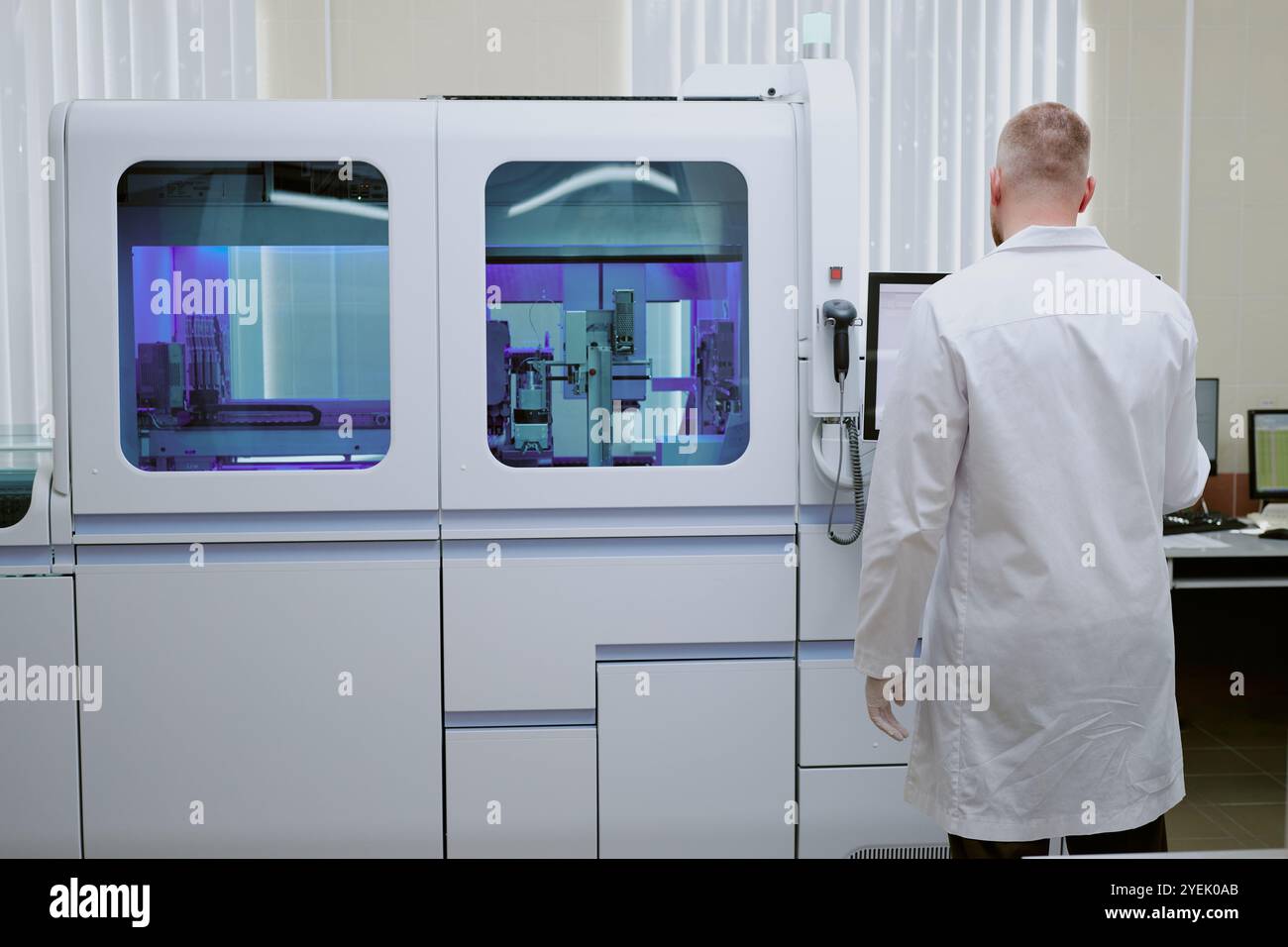 White-coated scientist operating modern laboratory equipment, immersed ...