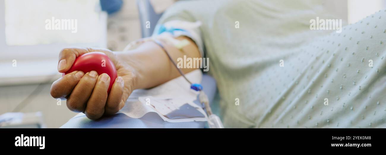 Close-up of a person donating blood at a medical clinic, holding a red ...