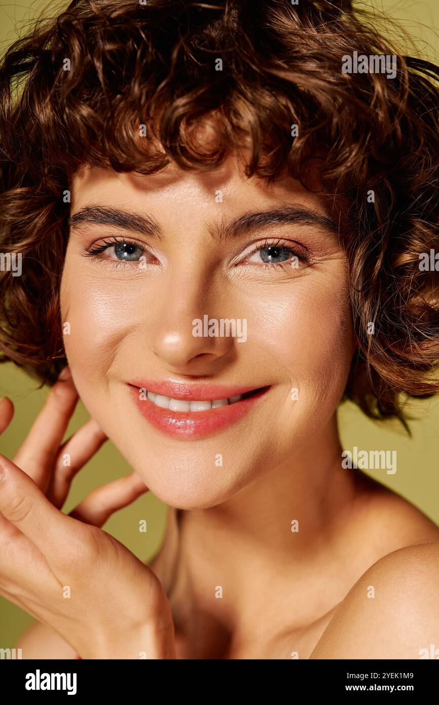 A young woman shares her infectious smile while lightly touching her ...