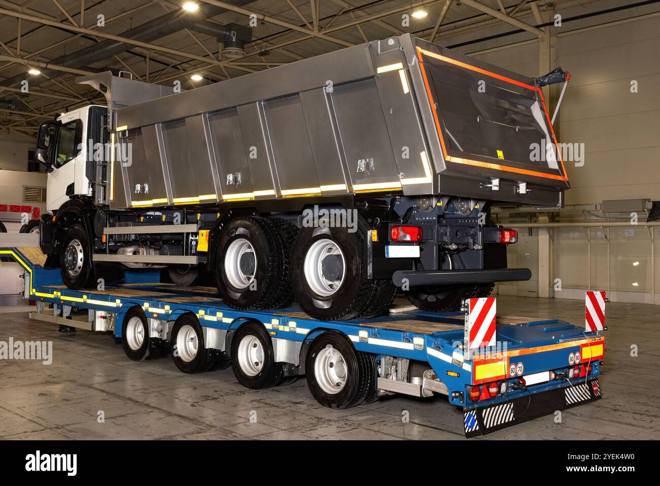 Brand new dump truck loaded on a low loader platform trailer, ready for ...