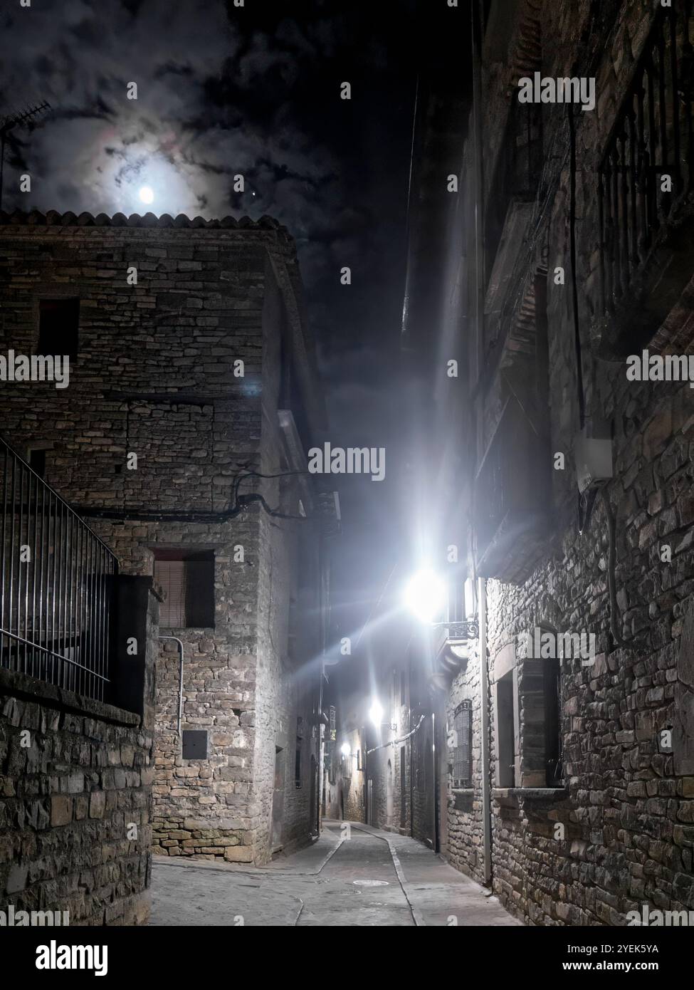 Narrow stone alley illuminated by street lamps and moonlight on a ...
