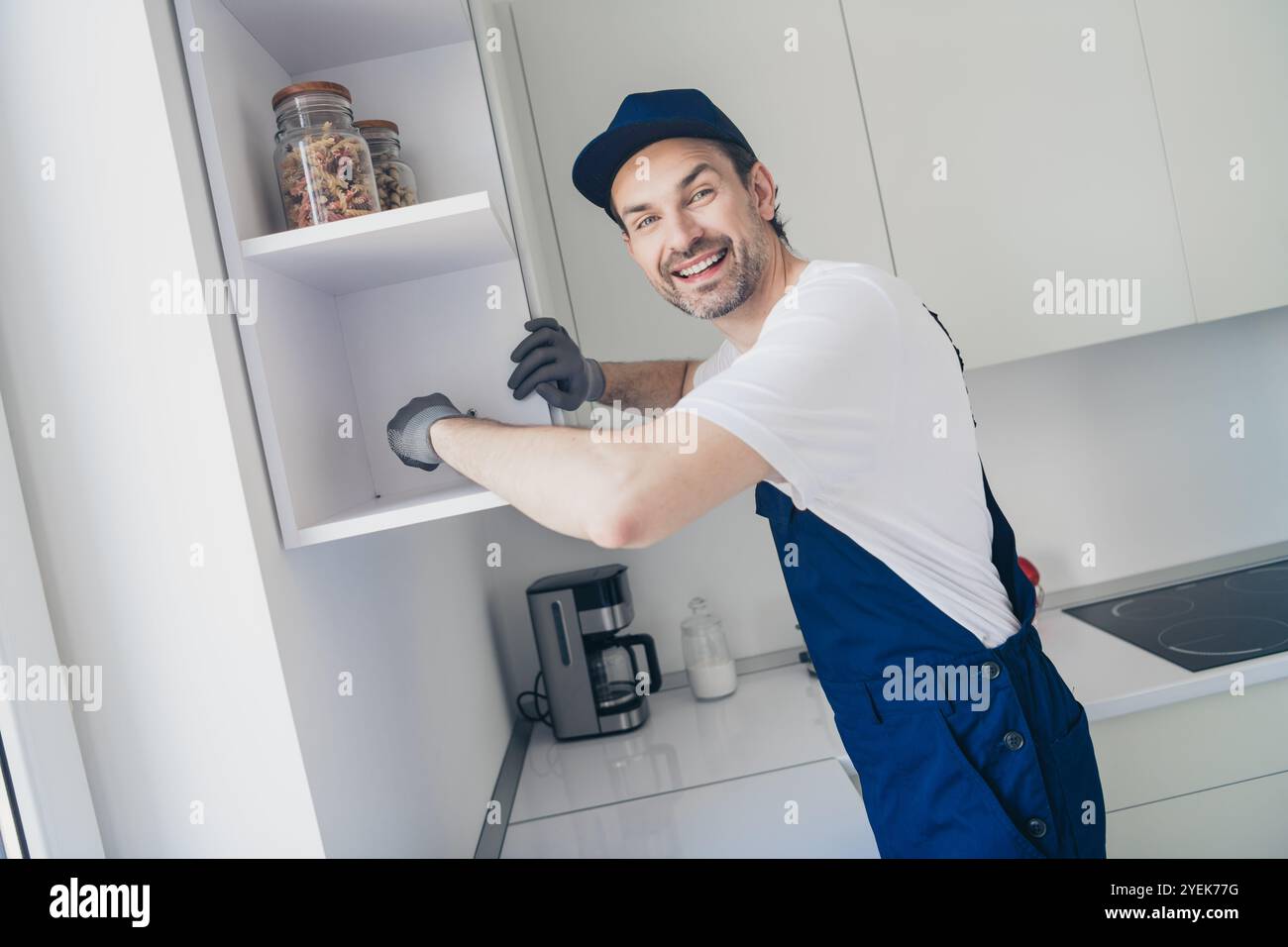 Cheerful handyman fixing kitchen cabinets, showcasing professionalism ...