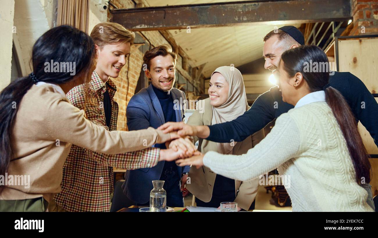 Multicultural team in open, relaxed office setting celebrates unity by ...