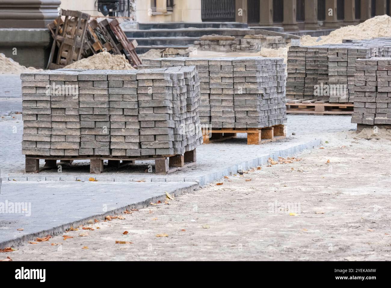 At a bustling construction site, neatly arranged stacks of paving ...