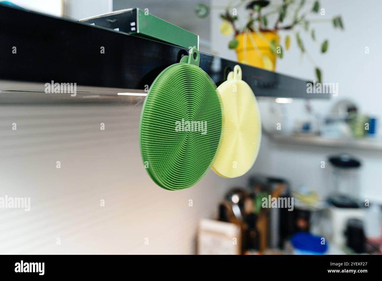 Green and yellow silicone dish scrubbers hang on a kitchen range hood ...
