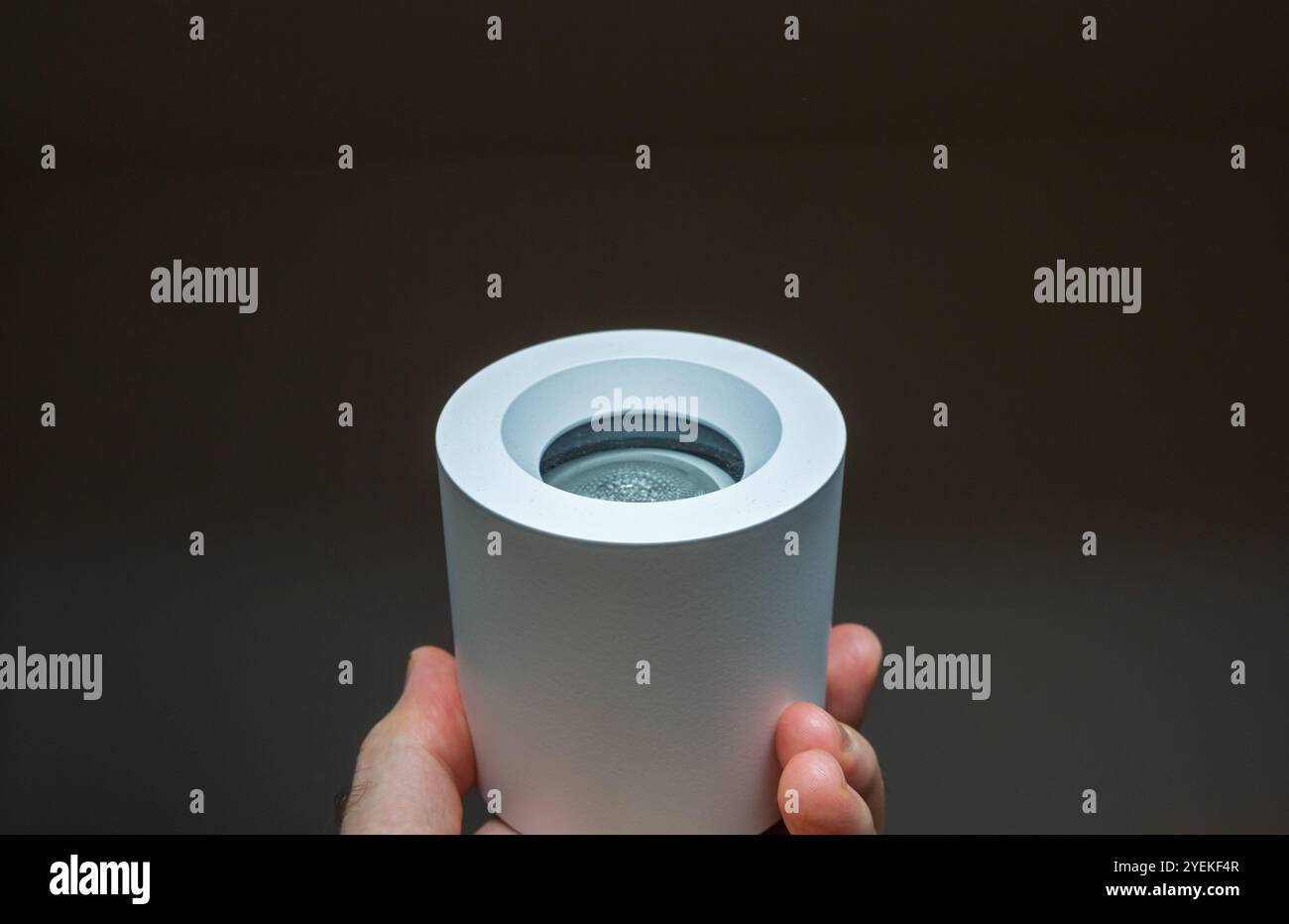 A cylindrical LED downlight held in a hand, showcasing the modern and ...