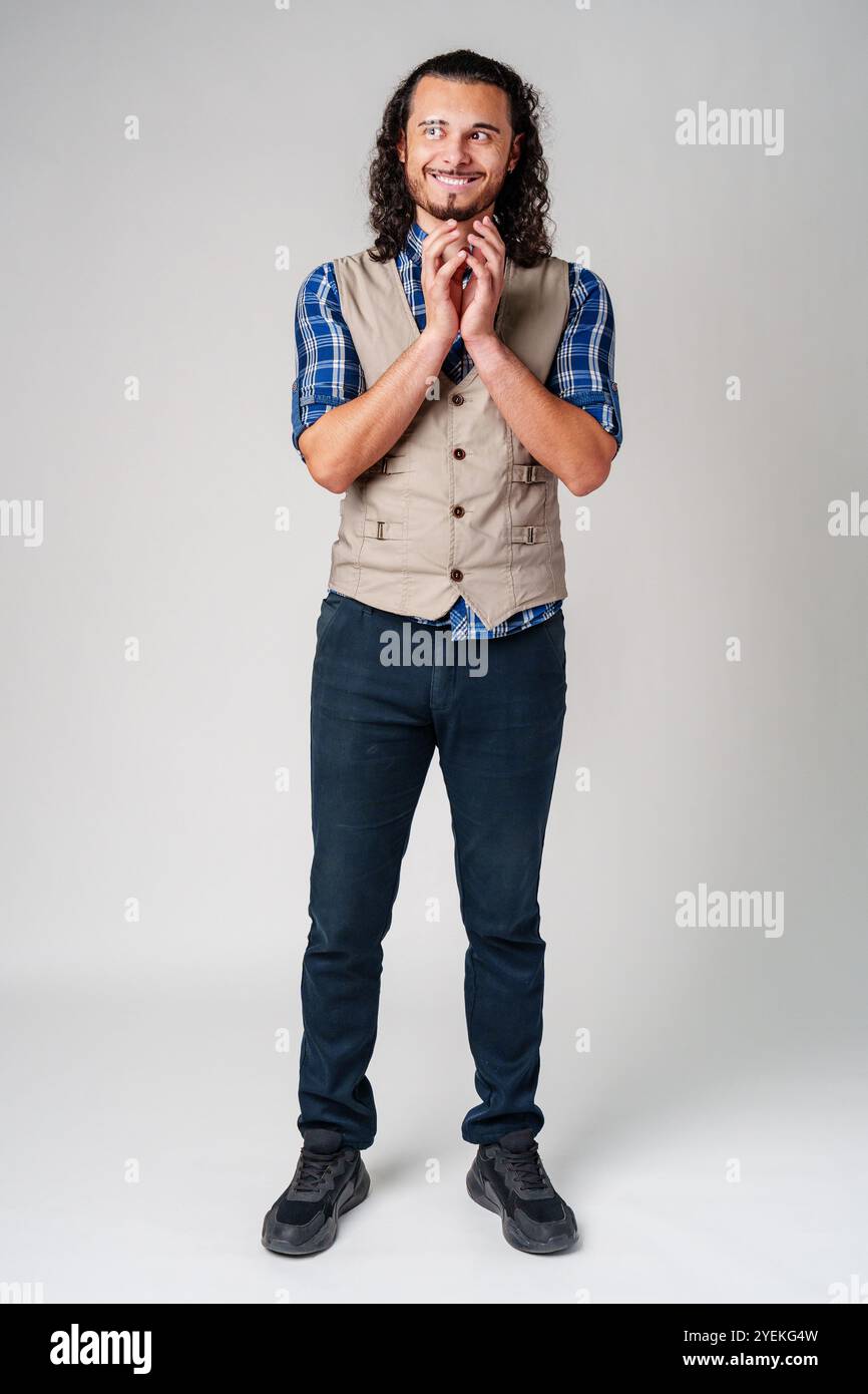 Man in a plaid shirt and vest stands smiling, looking optimistic in a ...