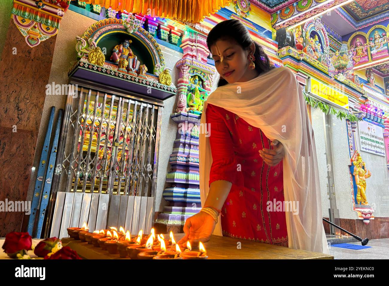 A Hindu devotee lights oil candles during their Diwali day at a temple ...
