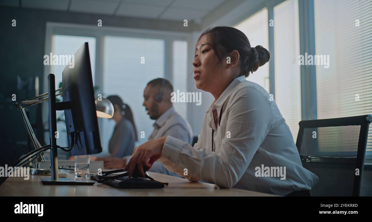 Call center office: Dolly shot of tired, stressed Asian hotline ...